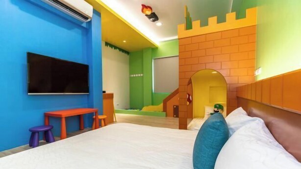 Quarto com cama, televisão, mesinha e escada que leva a uma área de recreação.