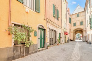 Rua estreita com edifícios e portas em arco e portaria verde.