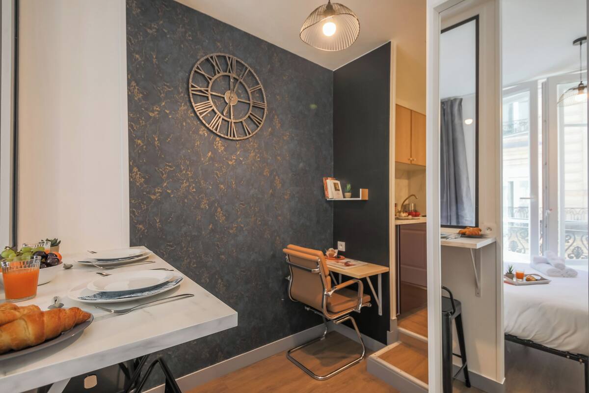 Quarto moderno com área de jantar, cama e vista para a cidade.
