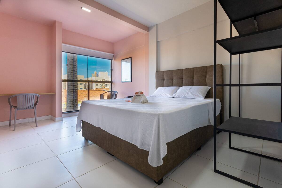 Quarto de hotel moderno com uma cama grande, uma escrivaninha e uma cadeira.