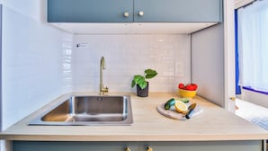 Uma cozinha moderna com uma pia de aço inoxidável, uma planta em vaso e produtos frescos no balcão.