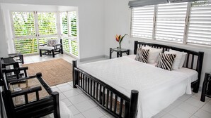 Quarto com uma cama grande, uma cadeira, uma mesa pequena e uma janela com persianas.