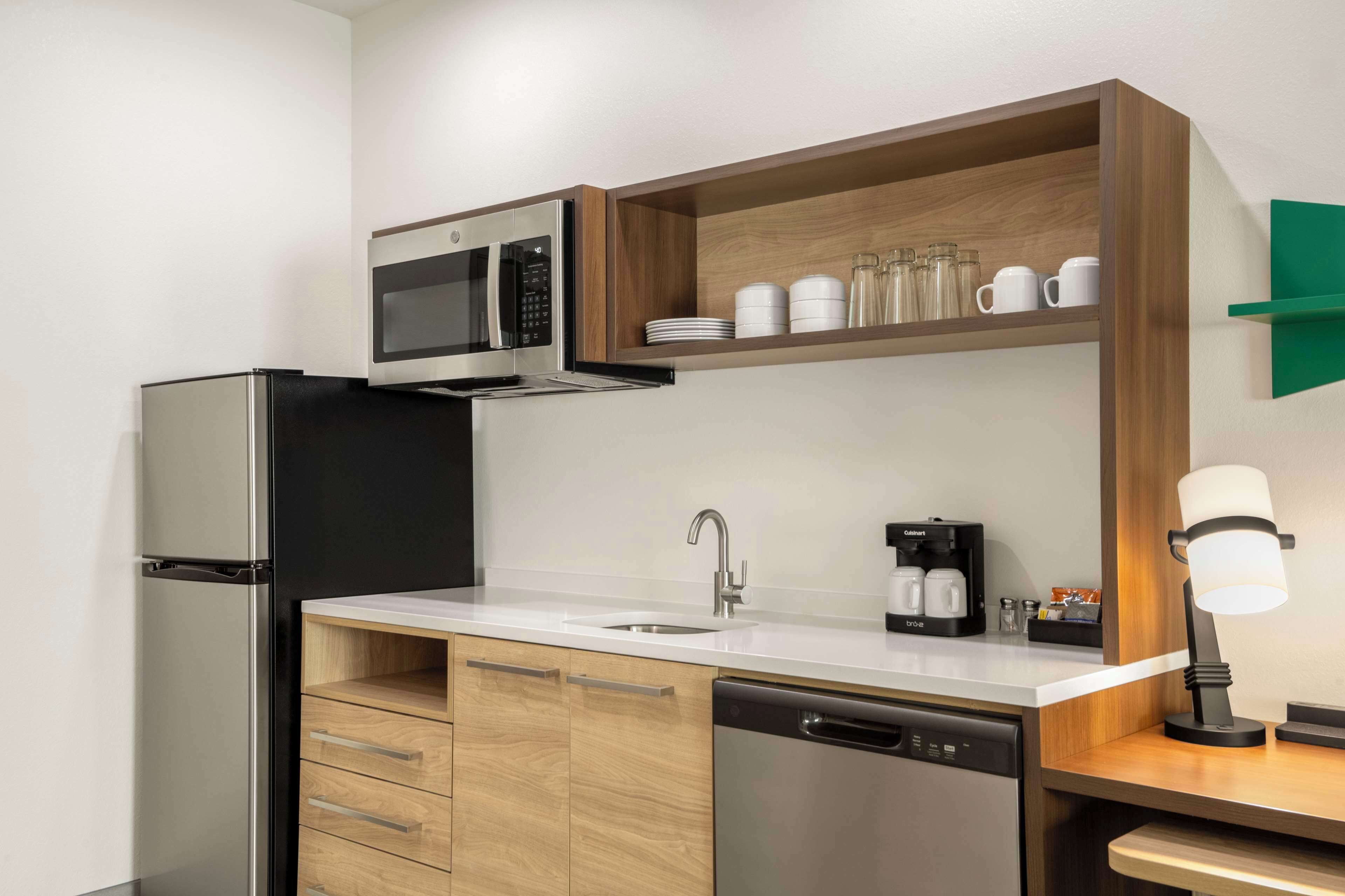 Cozinha compacta com micro-ondas embutido, máquina de café e lava-louças.