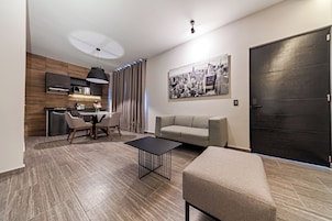 Uma sala moderna com área de jantar, sofá, mesa de centro e cozinha ao fundo.