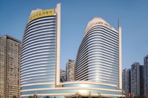 Um hotel moderno com fachada curva, duas torres imponentes e céu claro.