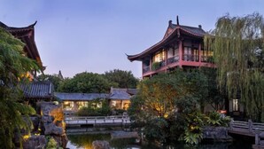 Um jardim chinês tradicional com lago, formações rochosas e arquitetura clássica.