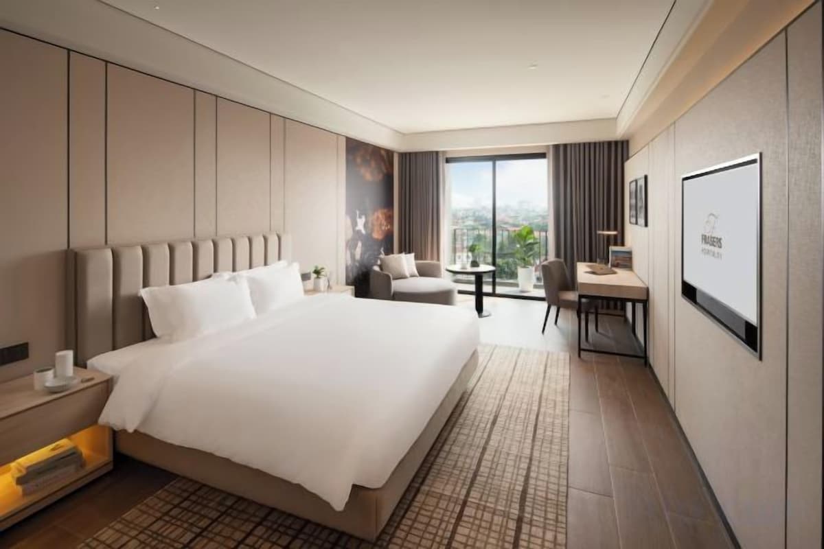 Quarto de hotel moderno com uma cama grande, uma escrivaninha e vista para a cidade.