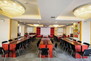 Uma sala de conferências com uma mesa comprida, várias cadeiras e uma tela de projetor.