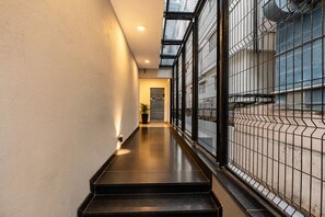 Um corredor com piso preto, uma planta em vaso e uma porta com a inscrição 'Wandell'.