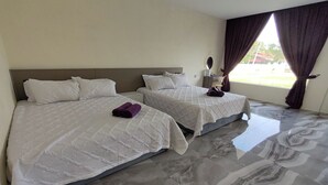 Quarto de hotel com duas camas, uma janela grande com cortinas e piso de mármore.