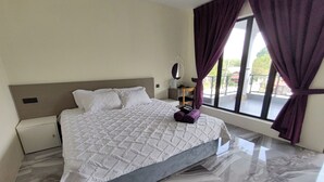 Quarto de hotel moderno com uma cama grande, mesa de cabeceira, escrivaninha e janela com cortinas.