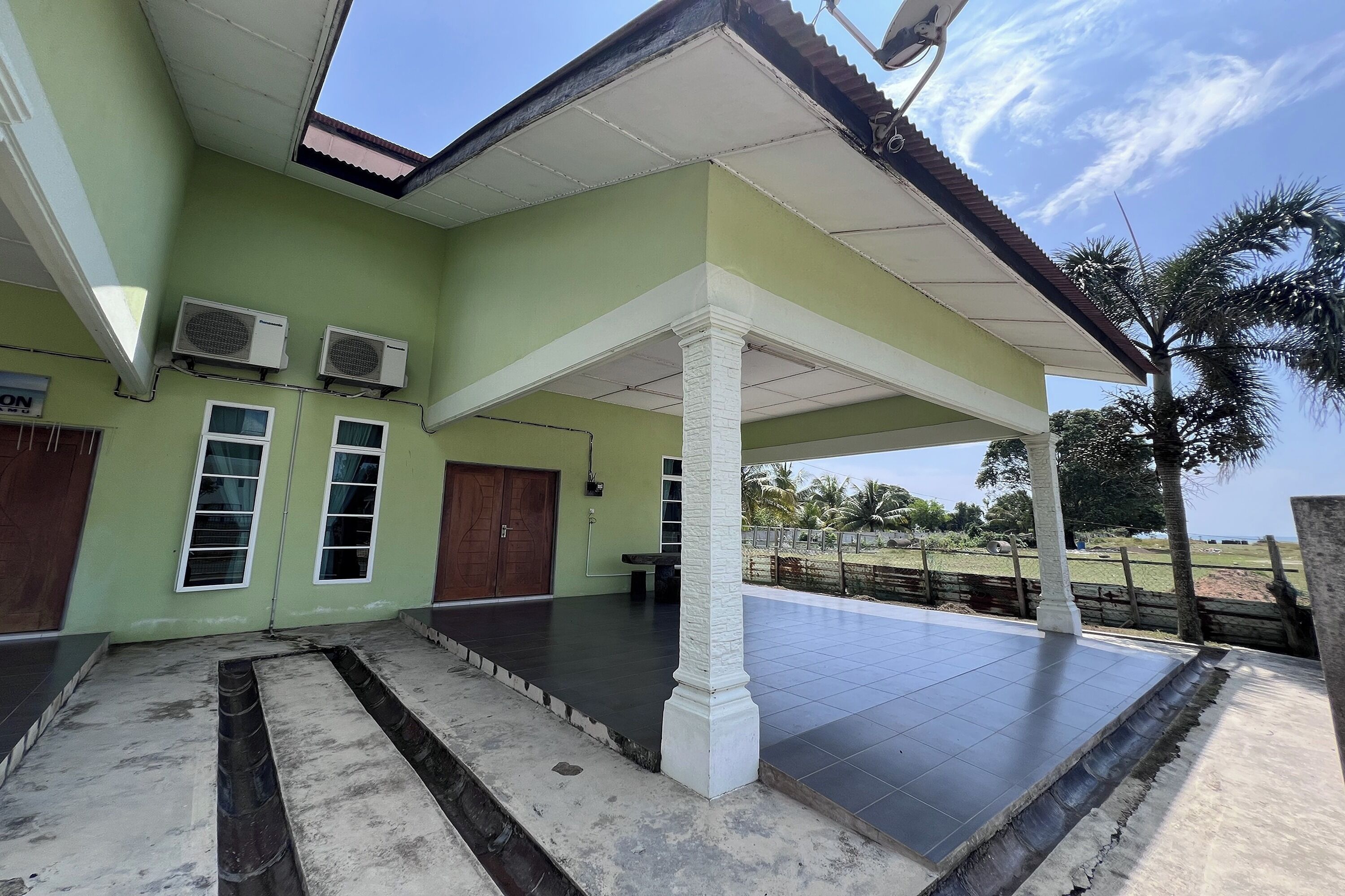 Um edifício com um terraço coberto, aparelhos de ar condicionado e piso ladrilhado.