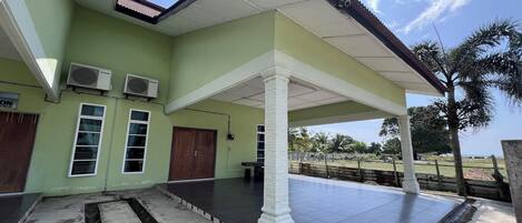 Um edifício com um terraço coberto, aparelhos de ar condicionado e piso ladrilhado.