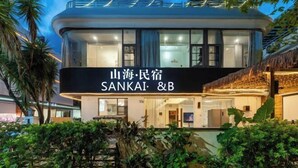 Um hotel moderno com fachada curva, grandes janelas e uma placa em chinês e inglês.