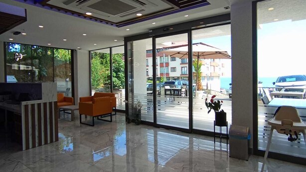 Um lobby moderno com balcão de recepção, área de estar e grandes portas de vidro que dão para o exterior.
