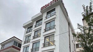 Hotel de vários andares com varandas, um carro estacionado na frente e área de estar externa.