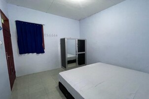 Quarto pequeno e limpo com uma cama de solteiro, um guarda-roupa e uma cortina azul.
