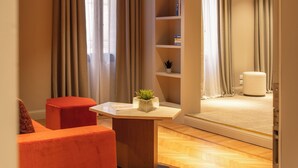 Uma sala de estar moderna com piso de madeira, um sofá vermelho, uma mesinha com uma planta e uma estante de livros.