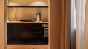 Uma cozinha com bancada preta, cafeteira e lava-louças.