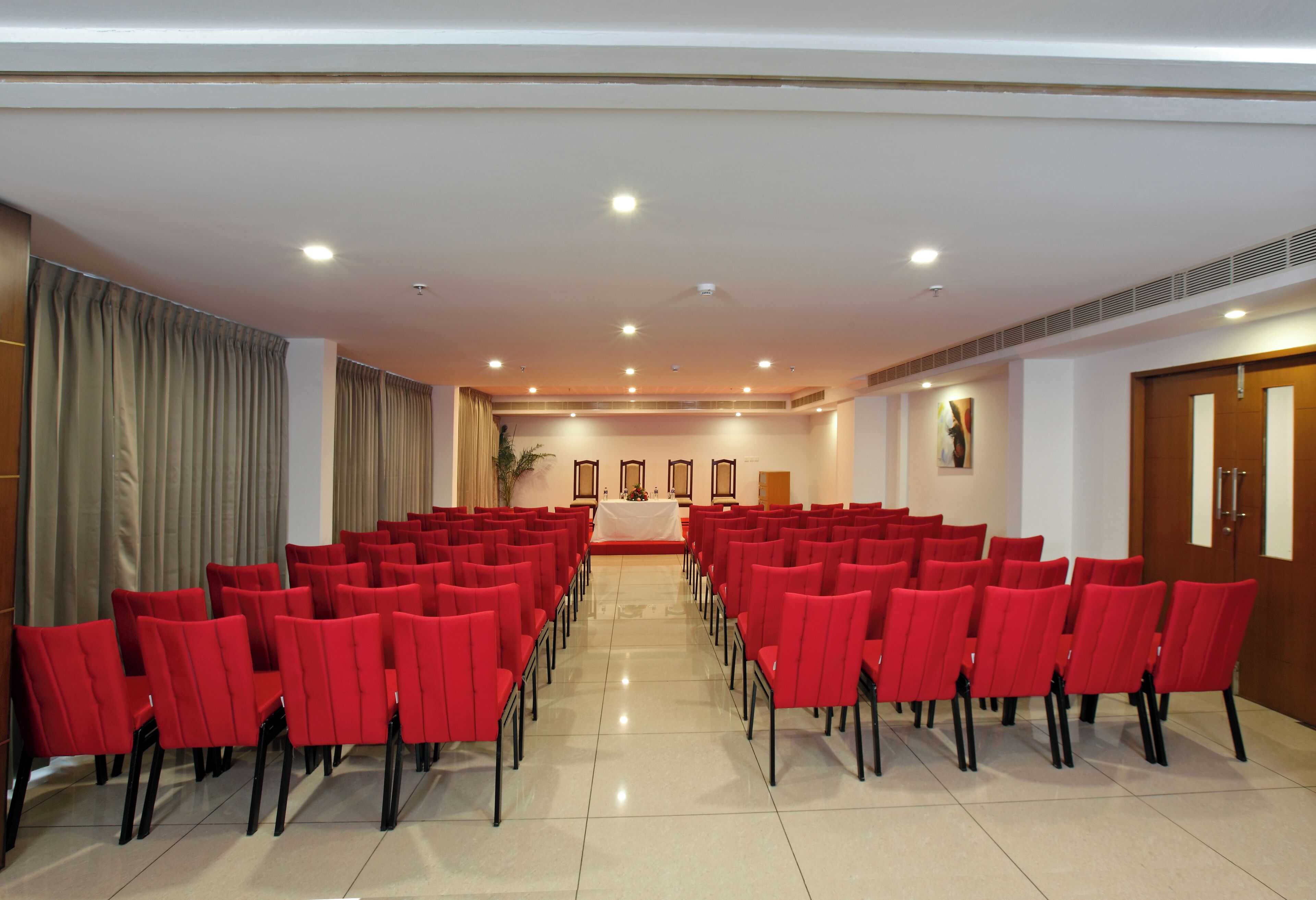 Sala de conferências com fileiras de cadeiras vermelhas voltadas para um palco com um púlpito.