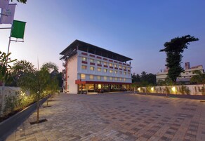 Um hotel com design moderno, apresentando um pátio espaçoso e um edifício grande com várias janelas.