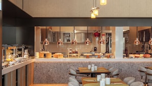Um restaurante moderno com um balcão extenso, diversas áreas de estar e iluminação pendente.