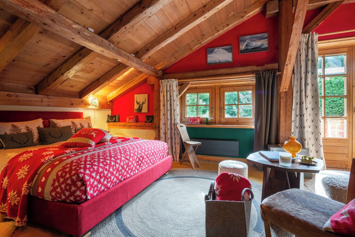 Quarto aconchegante com cama, mesa e janela com cortinas.