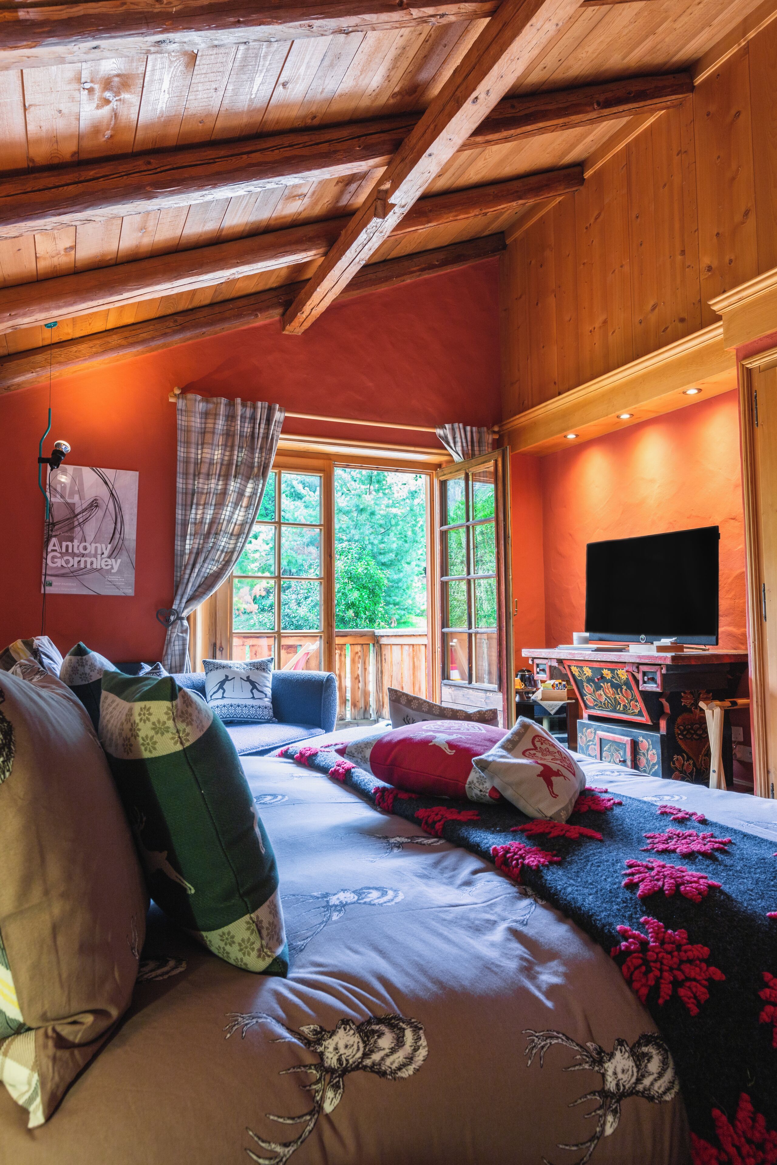 Um quarto acolhedor com uma cama, televisão e janela com cortinas.