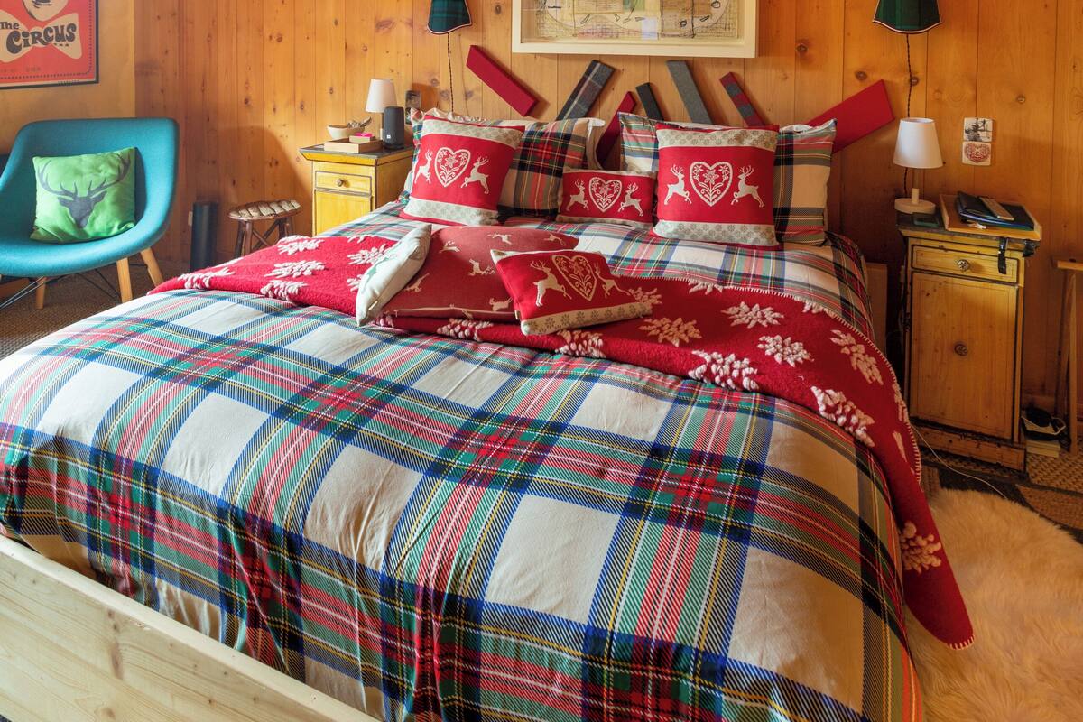 Quarto com painéis de madeira, uma cama, uma cadeira azul, um mapa na parede e um claraboia.