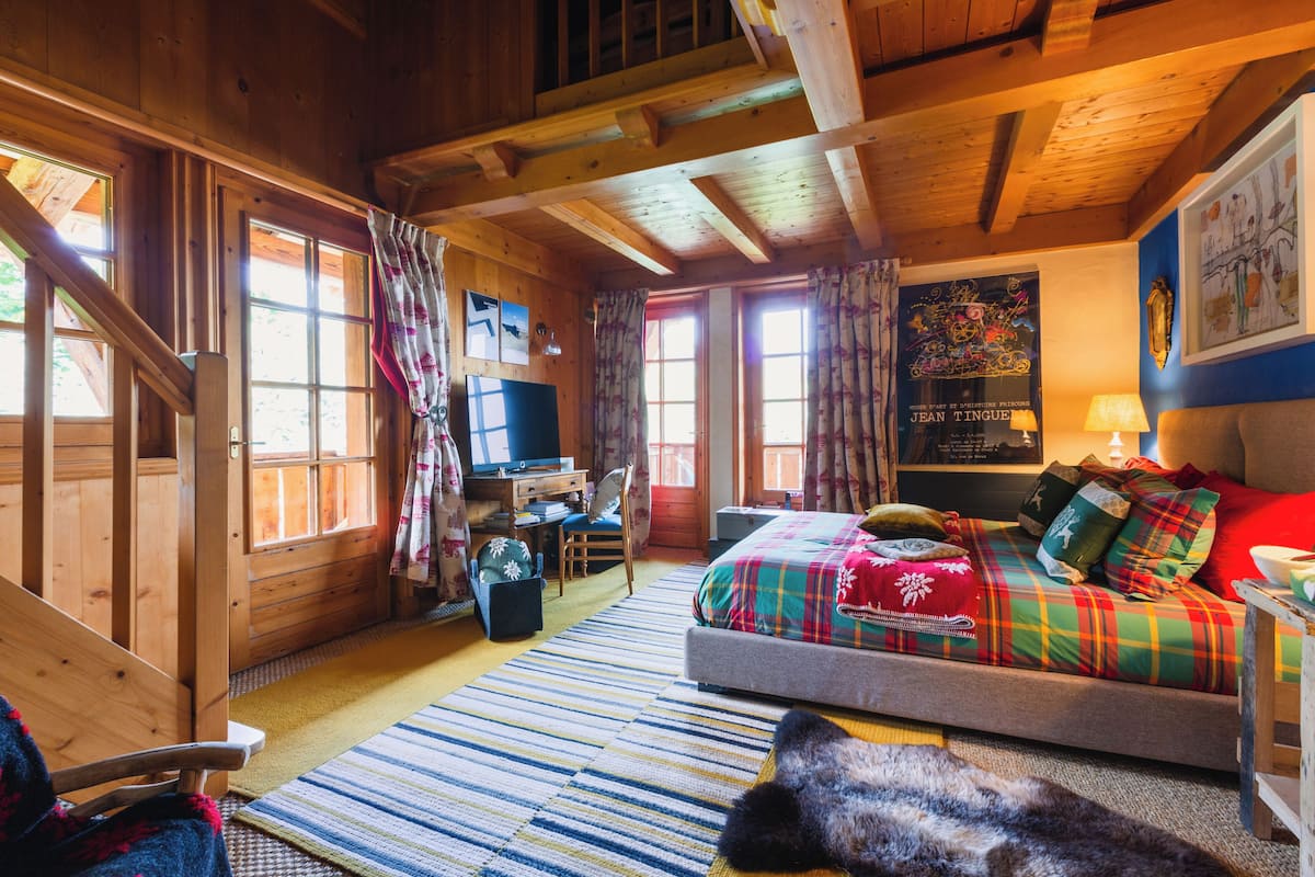 Um quarto aconchegante estilo cabana, com uma cama, escrivaninha e televisão.