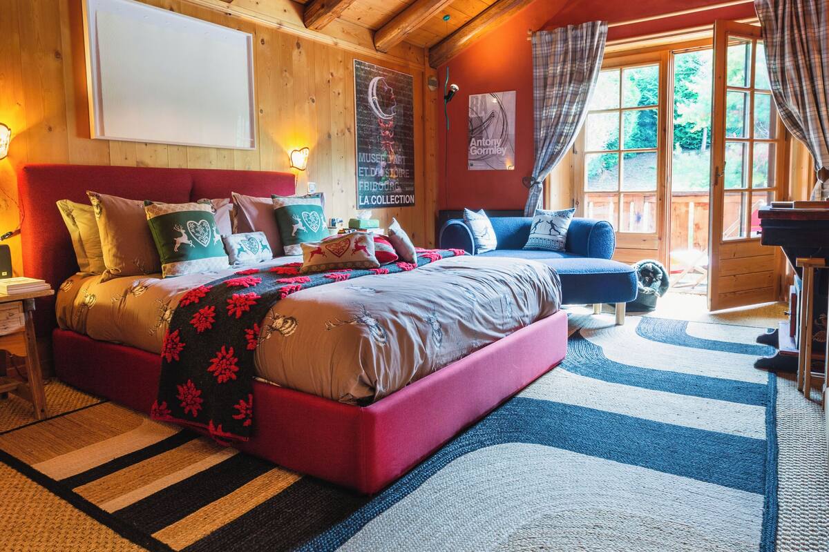 Quarto com uma cama grande, uma escrivaninha e uma janela com cortinas.