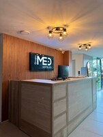 Uma receção de hotel com parede de painel de madeira, uma televisão e uma luminária moderna.