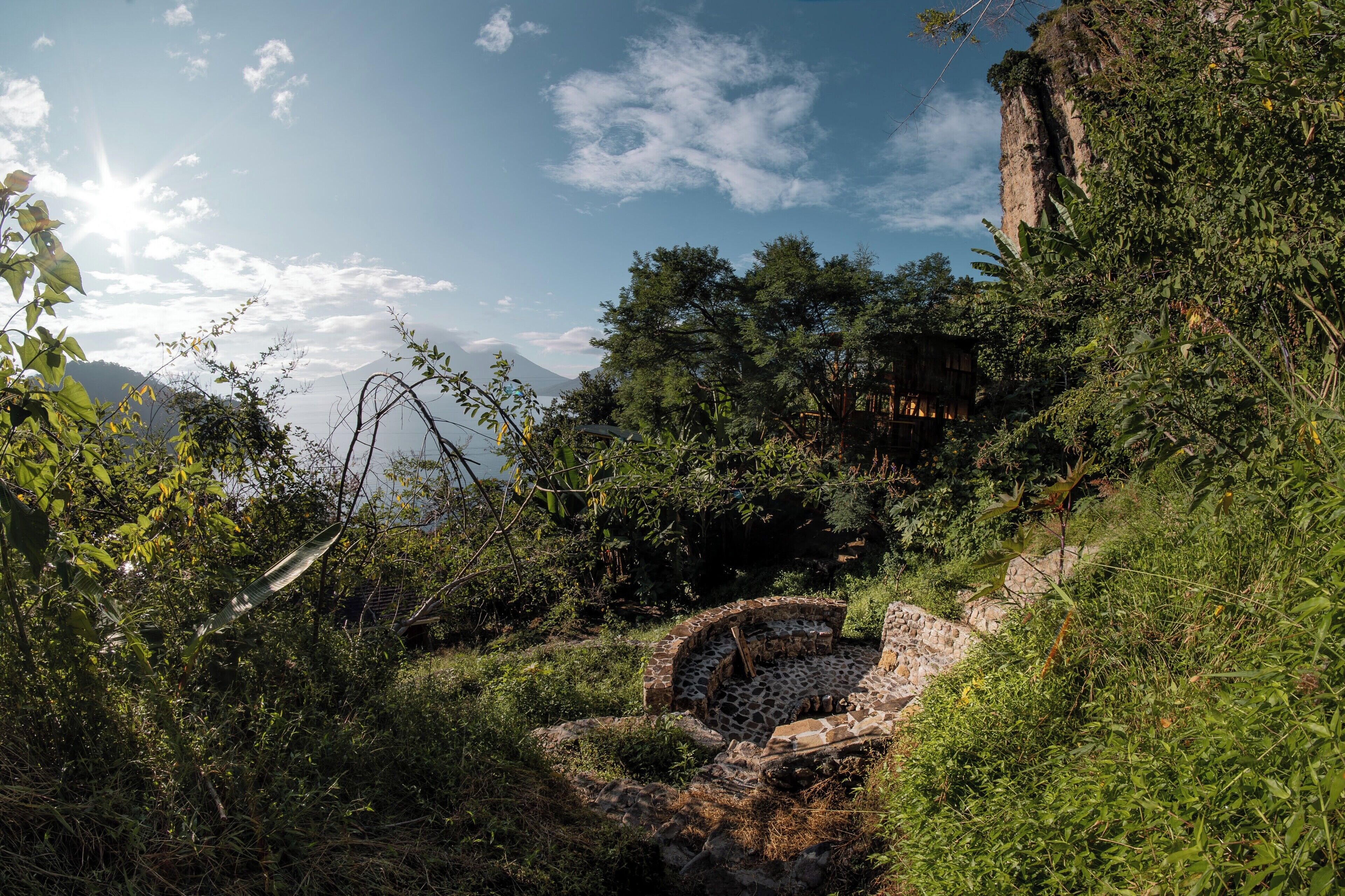 Uma construção de pedra rodeada por vegetação exuberante e um cenário montanhoso.