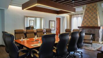 Uma sala de conferências com mesa de madeira, cadeiras pretas e lareira.