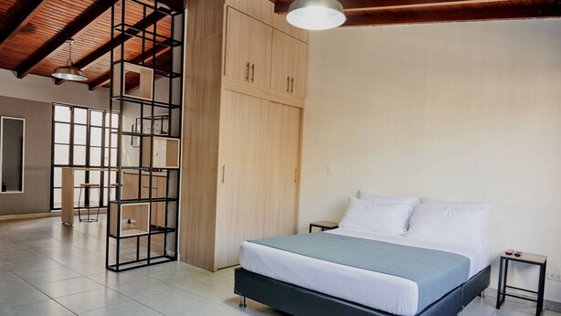 Quarto moderno com cama, guarda-roupa de madeira e estante embutida.