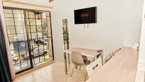 Quarto moderno com uma janela grande, televisão na parede, mesa de madeira e uma cadeira.