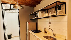 Uma cozinha moderna com geladeira de aço inoxidável, fogão a gás, pia e micro-ondas em uma prateleira.