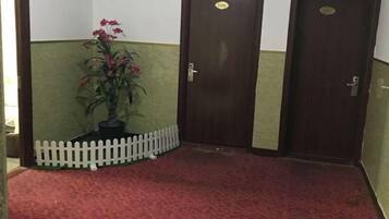 Um corredor com duas portas, cerca branca de piquete e um vaso com planta.