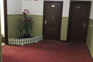 Um corredor com duas portas, cerca branca de piquete e um vaso com planta.