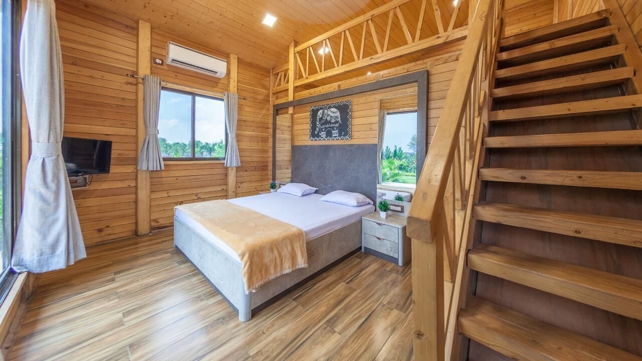 Quarto de cabana de madeira com cama, mesa de cabeceira e escada.