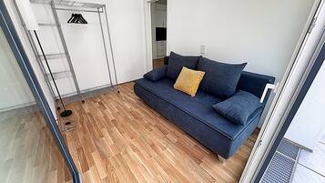Uma sala de estar moderna com um sofá azul escuro, piso de madeira e um varal de metal.