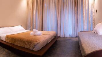 Quarto de hotel com cama, mesa de cabeceira e sofá.