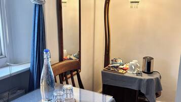 Quarto com mesa posta para refeições, espelho, lustre e cafeteira.
