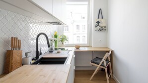 Uma cozinha moderna com bancada de madeira, pia e janela com vista para edifícios.