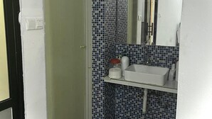 Um banheiro pequeno com pia branca, espelho e painel de azulejos.