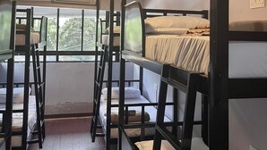 Um dormitório com beliches, uma escada, uma janela com vista e um ar condicionado na parede.