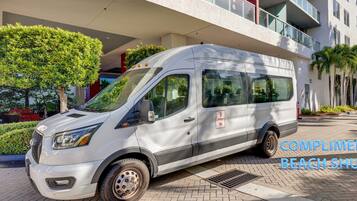Uma carrinha branca estacionada em frente a um edifício com fachada vermelha e branca.