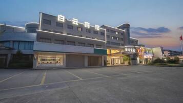 Um hotel moderno com uma placa chamativa, vários andares e um estacionamento.