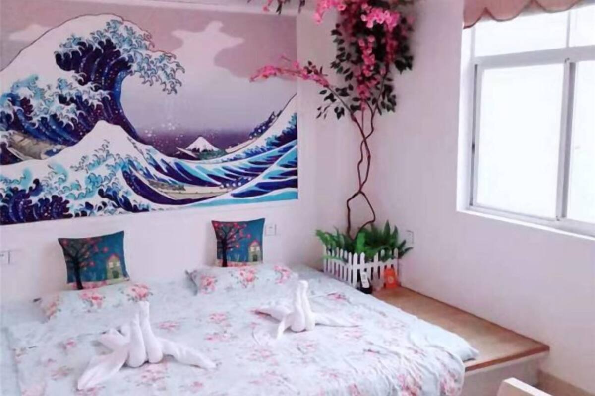 Quarto com pintura de ondas na parede, cama com roupa de cama floral e planta em vaso.