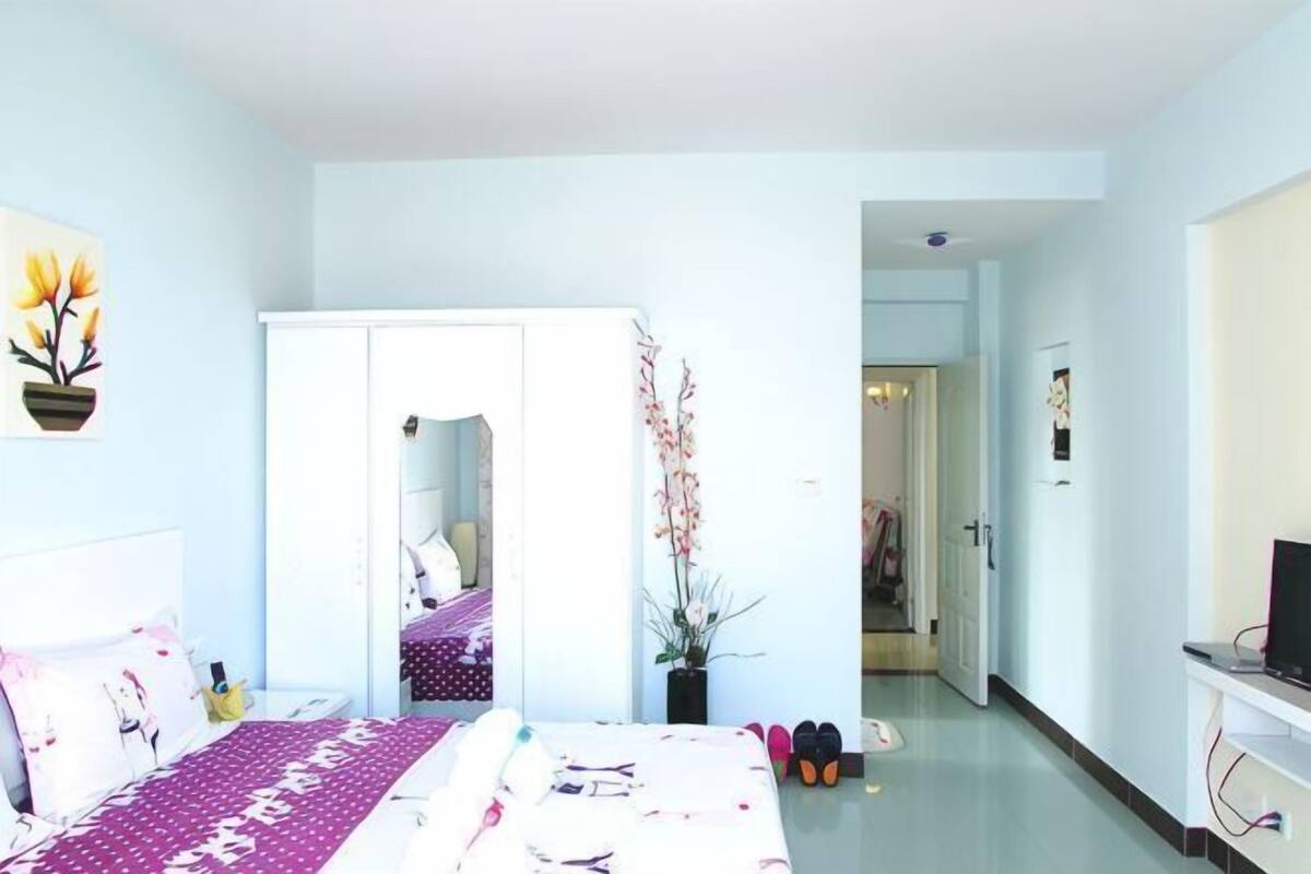 Quarto com cama, guarda-roupa, espelho e planta em vaso.